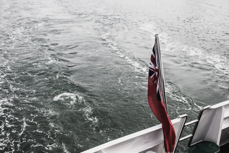 A Red Ensign Flag on the Back of a Ship with the Ships Wake in the ...