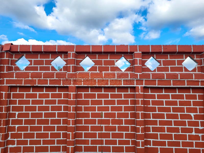 A Red Fence with Painted Bricks and Diamond Shaped Holes. Stock Photo ...