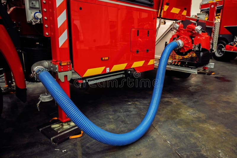 Red Fire Engine with Blue Hose Attached To Back Pumping System in a ...