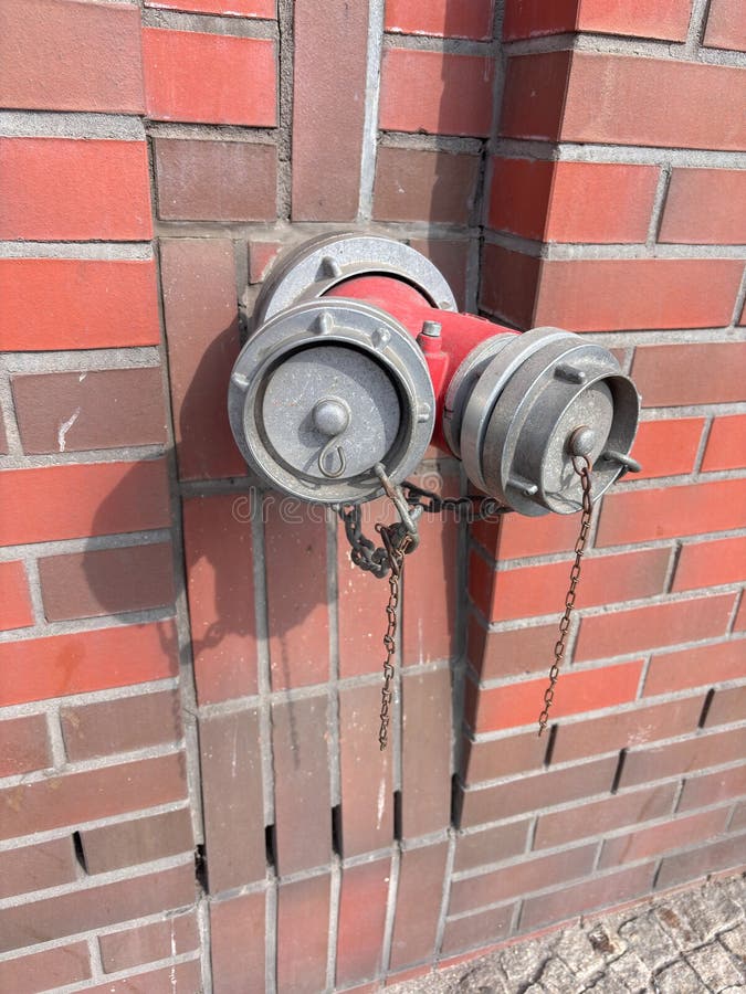 Red Fire Hydrant with Metal Connections on a Brick Wall for ...