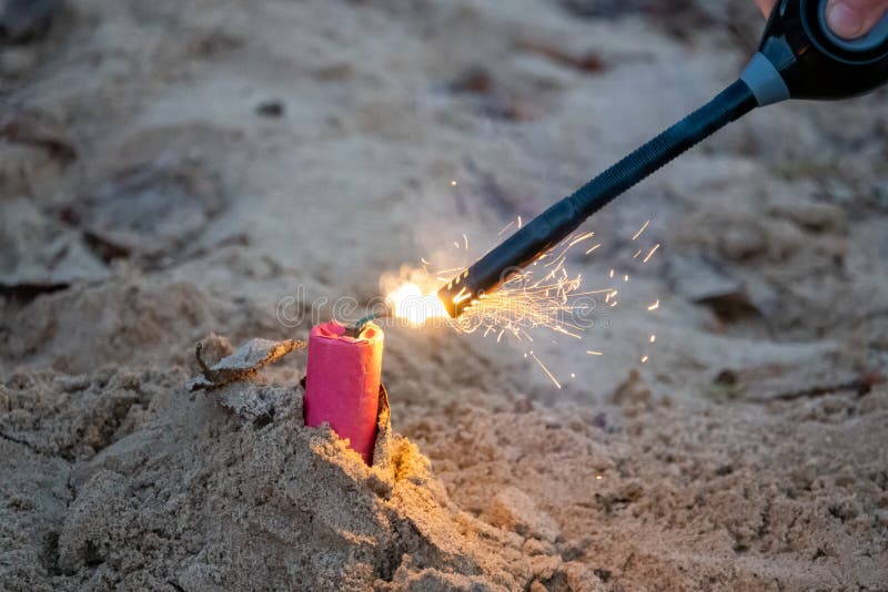 Red Firework Stuck in the Sand is Lit with a Black Stick Lighter Stock ...