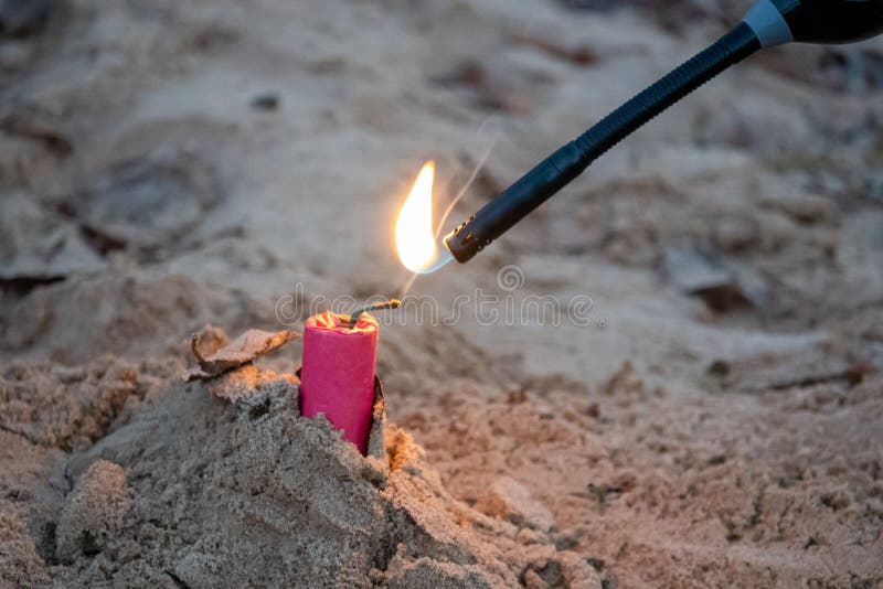 Red Firework Stuck in the Sand is Lit with a Black Stick Lighter Stock ...