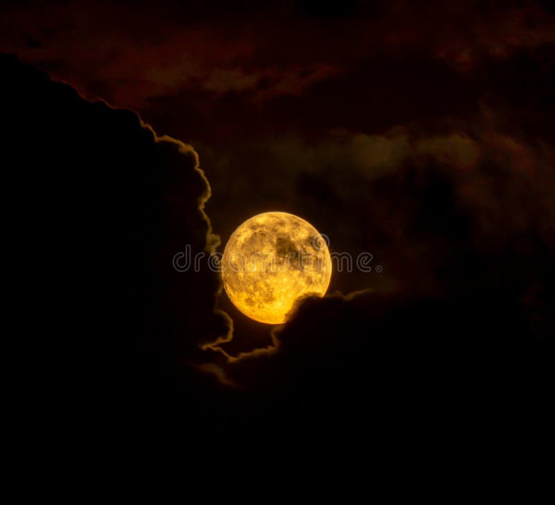 Red Full Moon Rising or Emerging from Clouds in Silhouette Illuminated ...