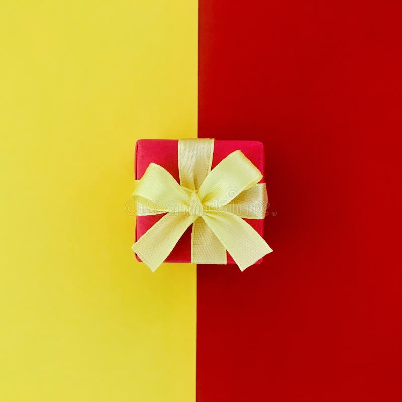 Red Gift Box with a Yellow Satin Ribbon Bow on Red and Yellow ...