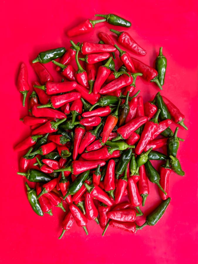 Red and Green Chilli Peppers. Heap on Red Background. Stock Photo ...