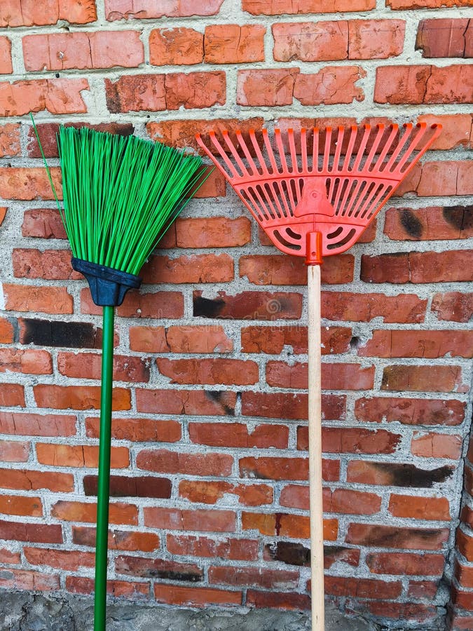A Red and Green Rake Leaning Against a Brick Wall Stock Photo - Image ...