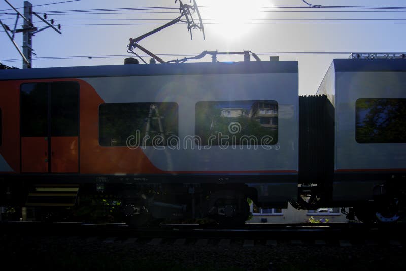 The Red-grey Train Sweeps through the Resort Town, the Sky is Reflected ...