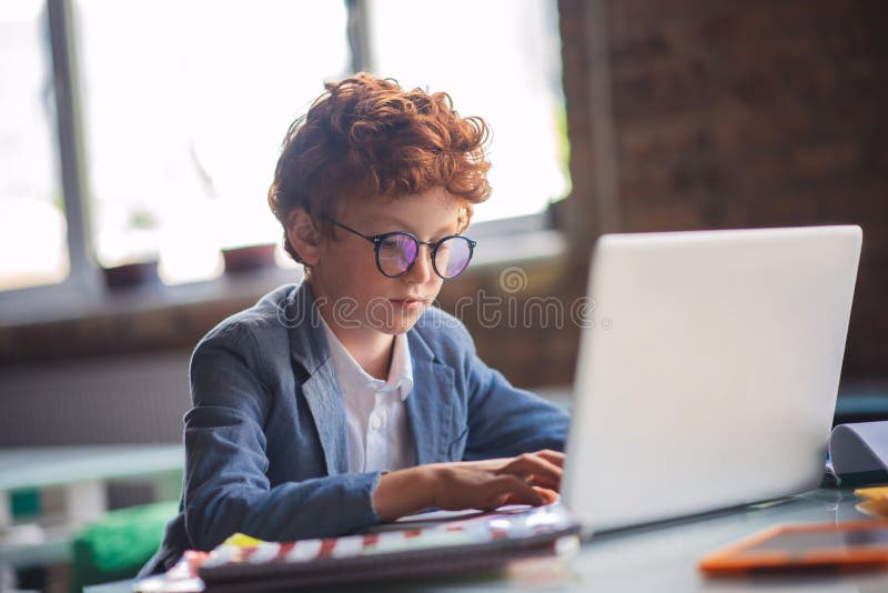 Red-haired Boy Sitting at the Laptop and Looking Busy Stock Photo ...
