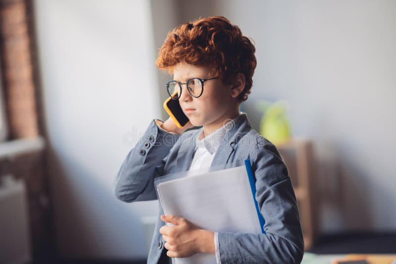 Red-haired Boy in a Suit Having a Phone Call and Looking Serious Stock ...