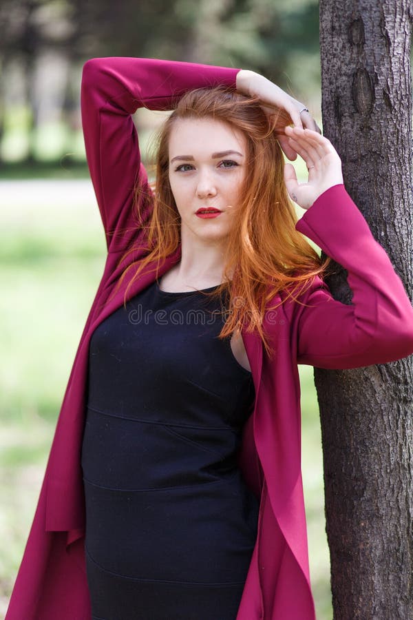 Red-haired Girl Posing Near a Tree in Red Clothes. Stock Photo - Image ...