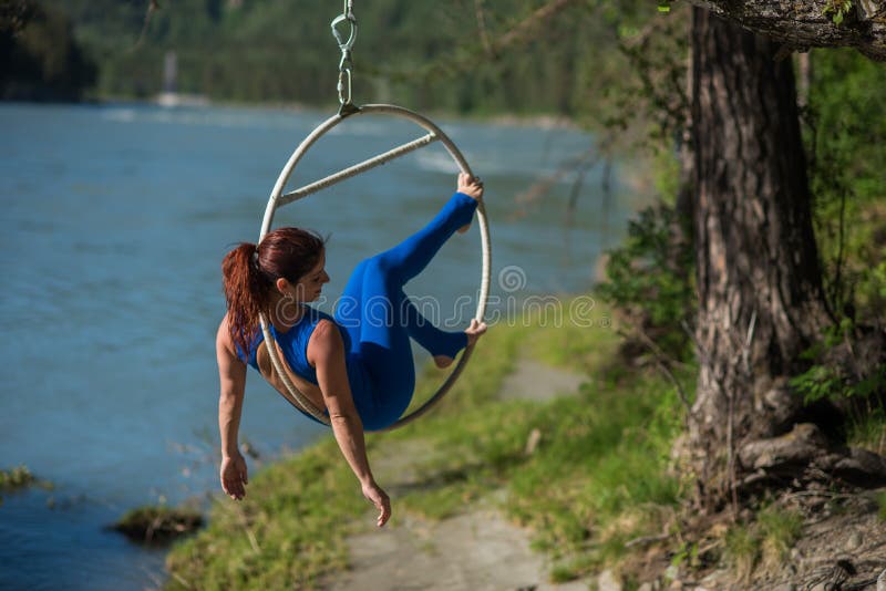 Red-haired Gymnast in a Blue Suit Doing the Difficult Exercises at the ...
