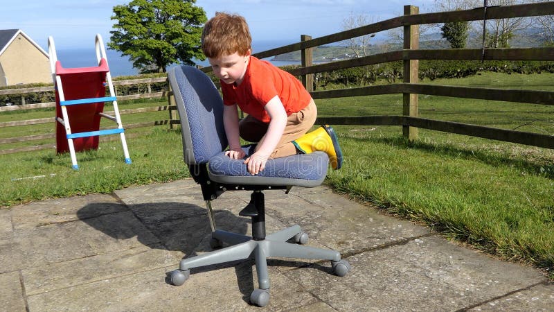 Red Headed Boy Having Fun Playing on a Chair in a Garden Stock Image ...