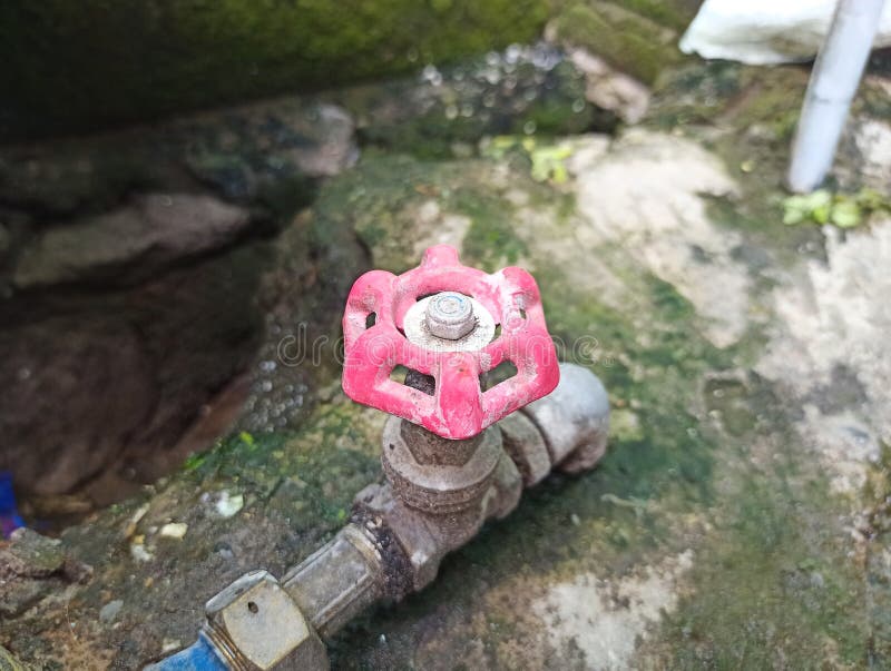 A Red Iron Water Valve, Showing Signs of Rust, is Connected To an Iron ...