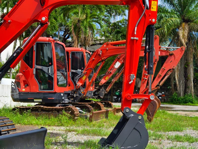 Red Large Excavators are Stationed in a Green Field in Front of a ...