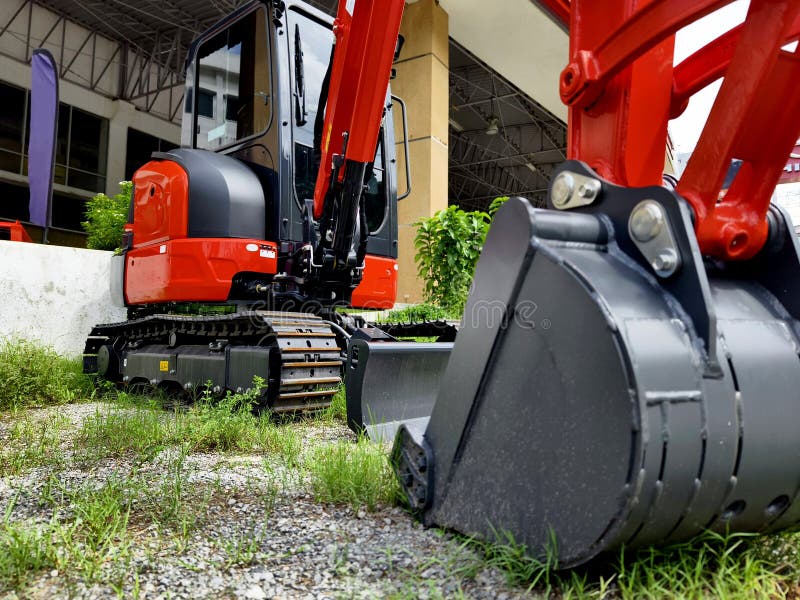 Red Large Excavators are Stationed in a Green Field in Front of a ...