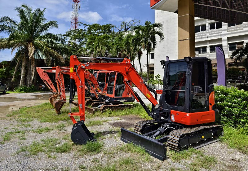 Red Large Excavators are Stationed in a Green Field in Front of a ...