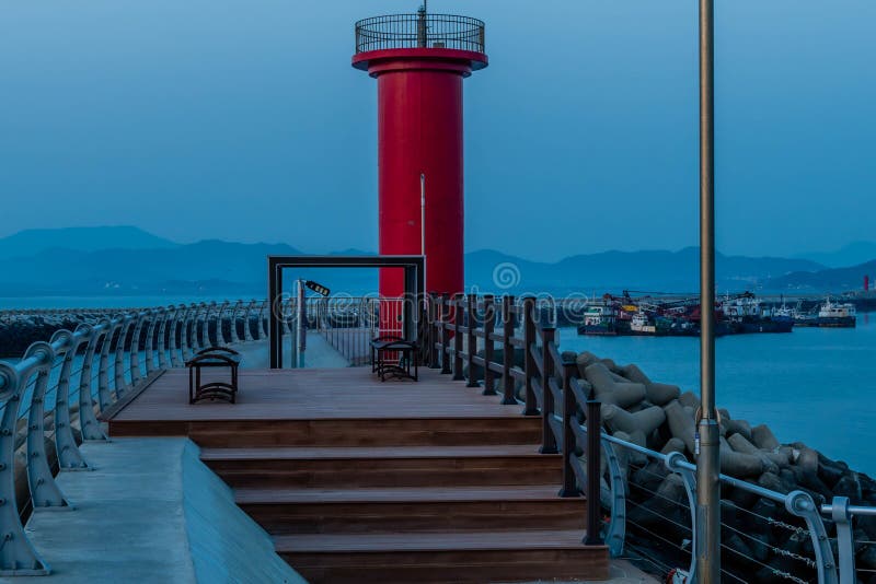Red Lighthouse on Pier with Hazy Blue Sky in Background Stock Photo ...