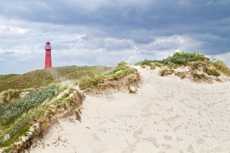 Red lighthouse and dunes stock photo. Image of blowing - 94301358