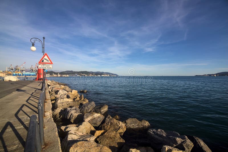 Red Lighthouse at the End of a Pier in a Bay with People Strolling and ...