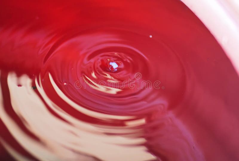 Close-Up of Red Liquid Surface with Concentric Ripples and Droplet ...