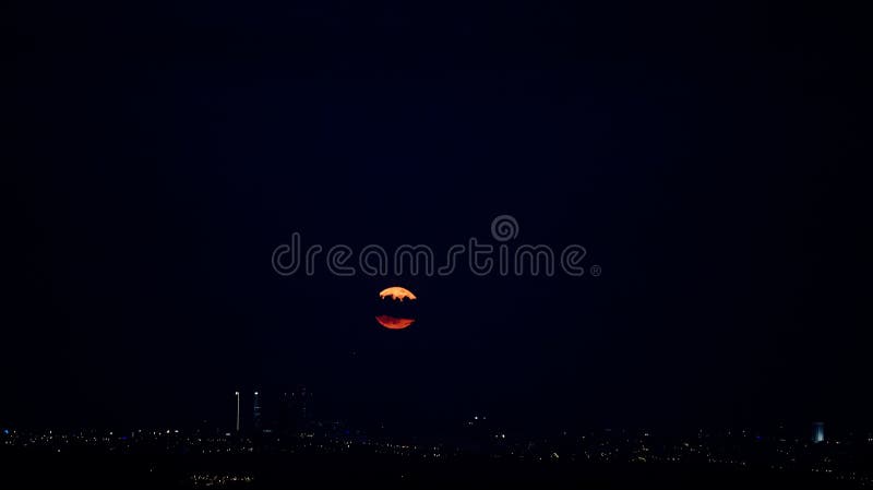 Red Moon of Eclipse between the Clouds Falling between Buildings of a ...