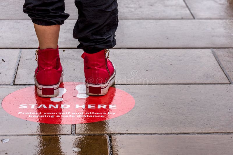 Red Pair of Shoes Standing on a Red Sign Saying Stand Here To Avoid ...