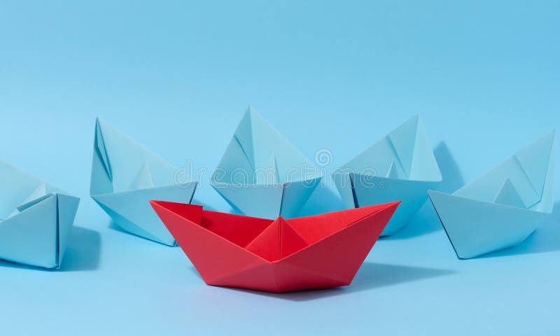 A Red Paper Boat Stands in Front of a Group of Blue Paper Boats, a ...