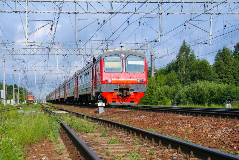 Passenger Electric Train Moves Against the Background of Green Trees ...