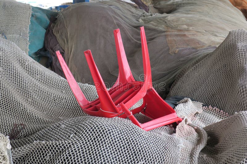 Red Plastic Chair Laying on a Heap of Fishing Nets Stock Image - Image ...