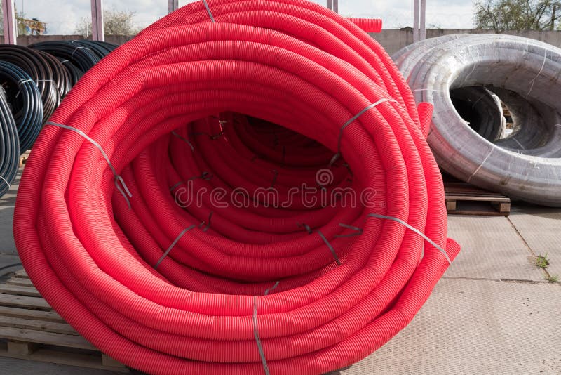 Red Plastic Pipes Rolled into Open Air Rolls. Construction Site Stock ...