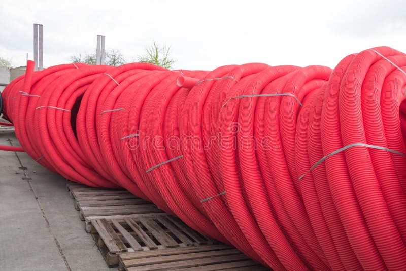 Red Plastic Pipes Rolled into Open Air Rolls. Construction Site Stock ...