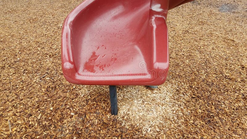 Red Plastic Playground Slide with Wood Chips on Ground Stock Photo ...