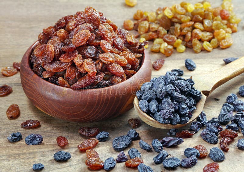 Red Raisins in a Bowl on a Wooden Table. Black Raisins in a Spoon ...