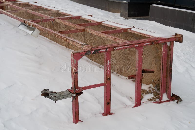 Red Rusty Construction Cradle Lies on Its Side in the Snow Next To the ...