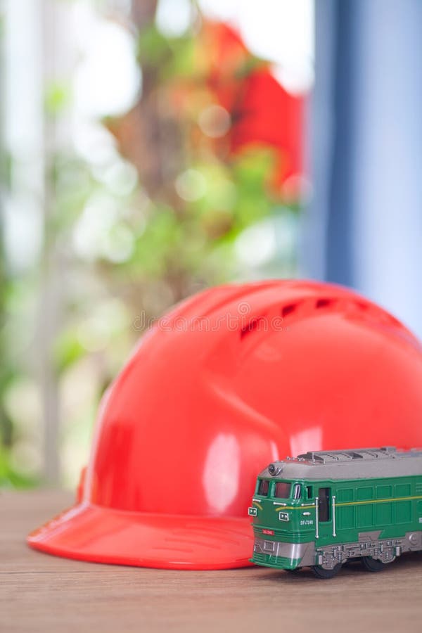 Red Safety Helmet and a Green Leather Train Model on the Table Stock ...