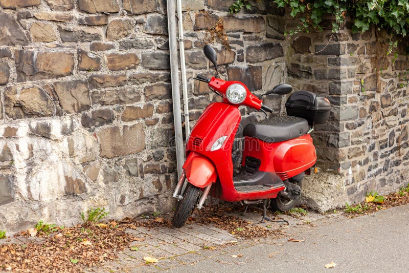 Red Scooter Parked on the Street in Front of a Stone Wall Stock Photo ...