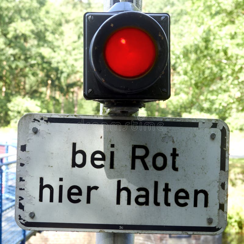 Red Shining Light Above a Sign with the German Inscription: Stop Here ...