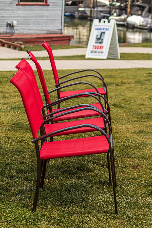 Red Stackable Chairs in a Row on Grass during Summer Park Show Stock ...
