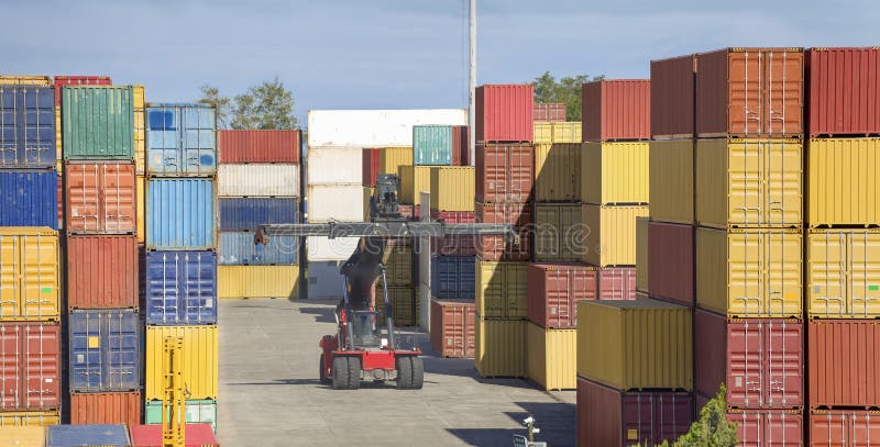 A Red Stacker Drives Along the Rows of Shipping Containers at the Port ...