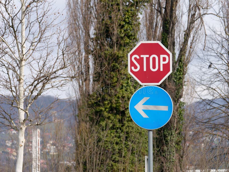 Red Stop Sign and a Turn Left Sign on the Road Stock Photo - Image of ...