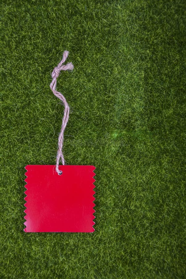Red tag on a green grass stock image. Image of abstract - 102685607