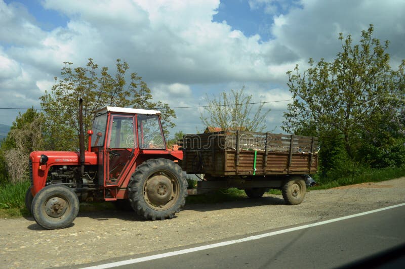 Red Tractor with a Trailer Parked on the Side of the Road Stock Photo ...