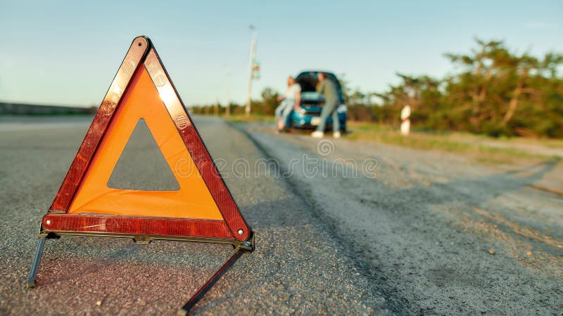 Red Warning Triangle Sign on the Road with a Couple Checking, Standing ...