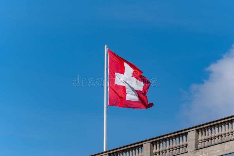 A Red and White Flag with a Cross on it is Flying in the Sky Stock ...