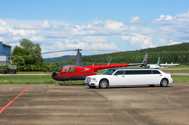 A Red and White Helicopter is Parked on the Ground Next To a White ...
