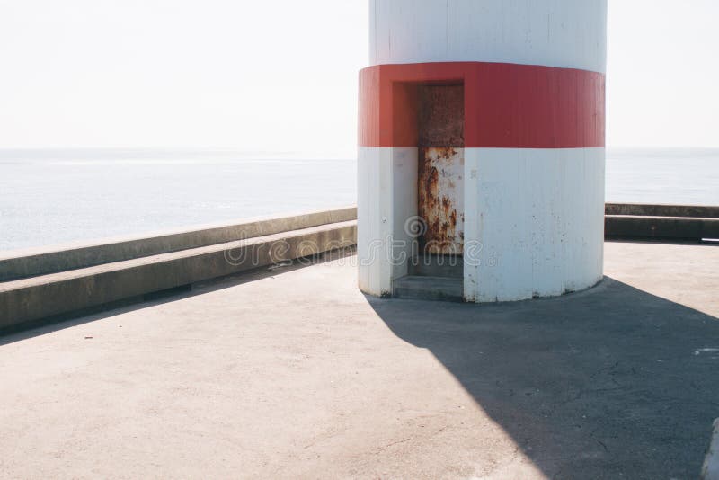 Red and White Striped Lighthouse with a Rusty Door on a Pier Stock ...
