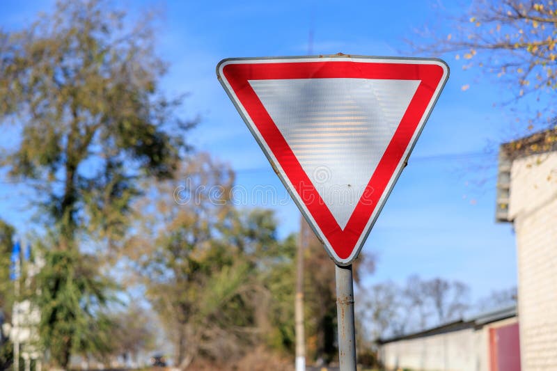 A Red and White Triangular Sign with a White Arrow Pointing To the Left ...