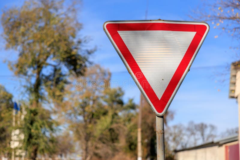 A Red and White Triangular Sign with a White Arrow Pointing To the Left ...
