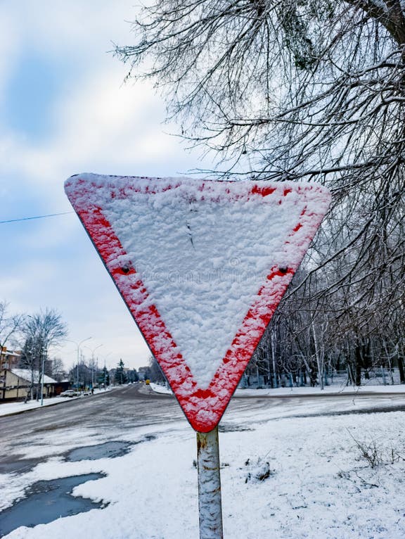 A Red and White Triangular Sign Sitting on the Side of a Road Covered ...