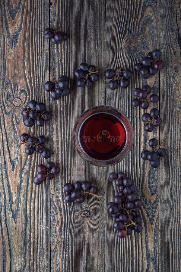 Red Wine in a Glass and Grapes on an Old Wooden Table Stock Photo ...
